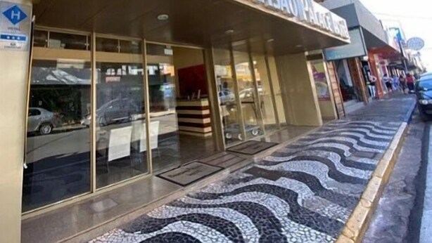 Entrada de hotel com fachada de vidro e design de piso estampado.