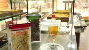 Disposição de buffet com diversos recipientes de comida e uma garrafa de molho.