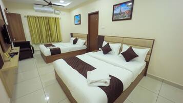 Quarto de hotel com duas camas, uma mesa, uma cadeira e um ventilador de teto.