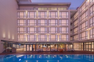 Um hotel moderno com piscina, área de estar externa e vários andares.