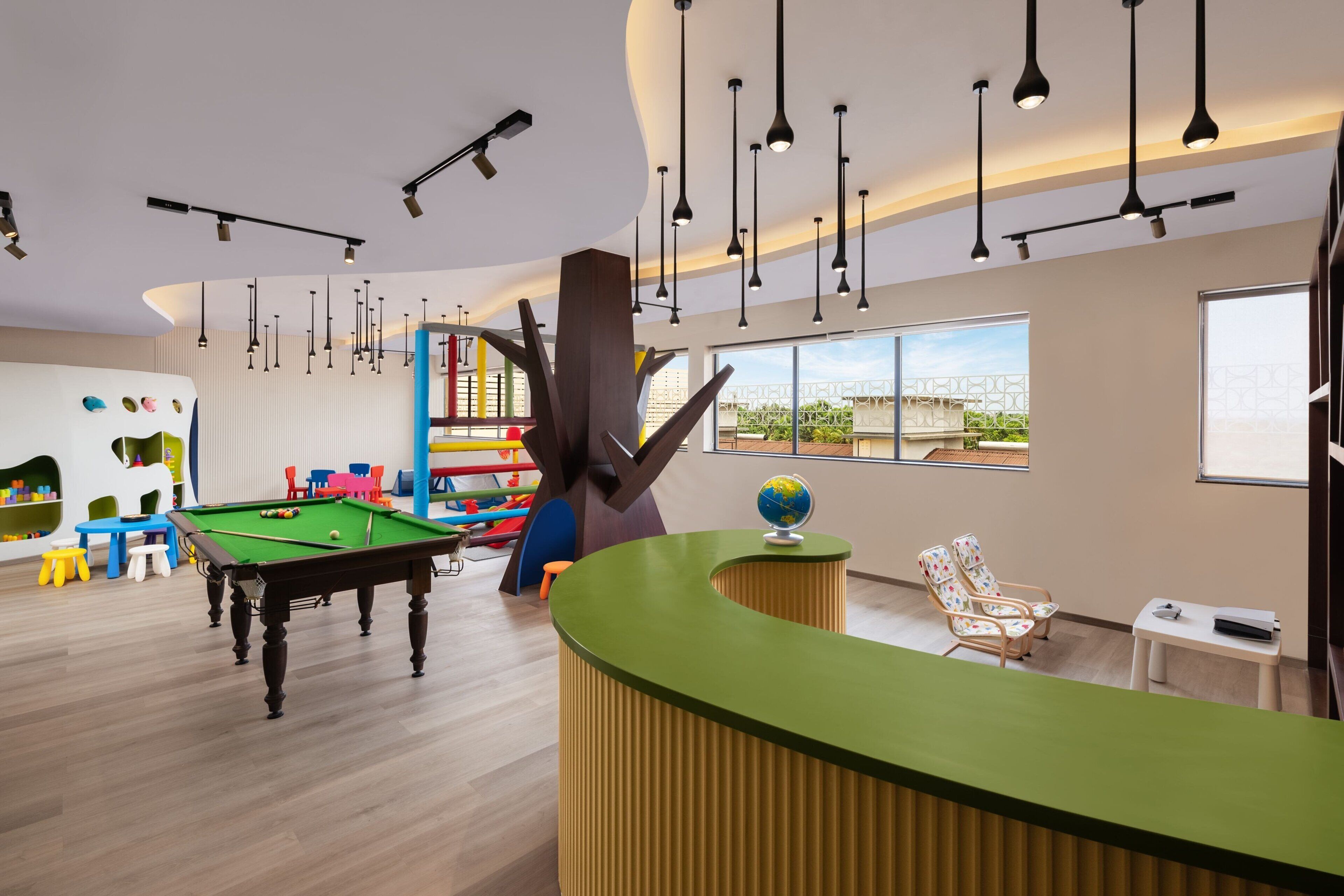 Espaço moderno com mesa de bilhar, área de recreação colorida e balcão de recepção.