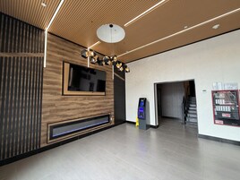 Um lobby moderno com televisão de tela plana, um totem digital e uma máquina de venda automática.