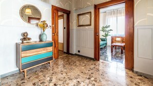 Um corredor com um console de madeira, um espelho e um vaso com flores.