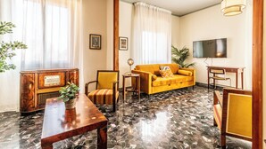 Uma sala de estar com sofá, poltronas, mesa de centro de madeira, televisão e uma planta.