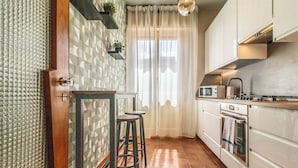 Cozinha com painel decorativo, fogão, forno e dois banquetes.