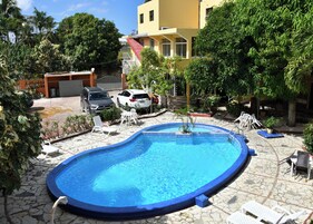 Piscina com espreguiçadeiras e um pequeno jardim.