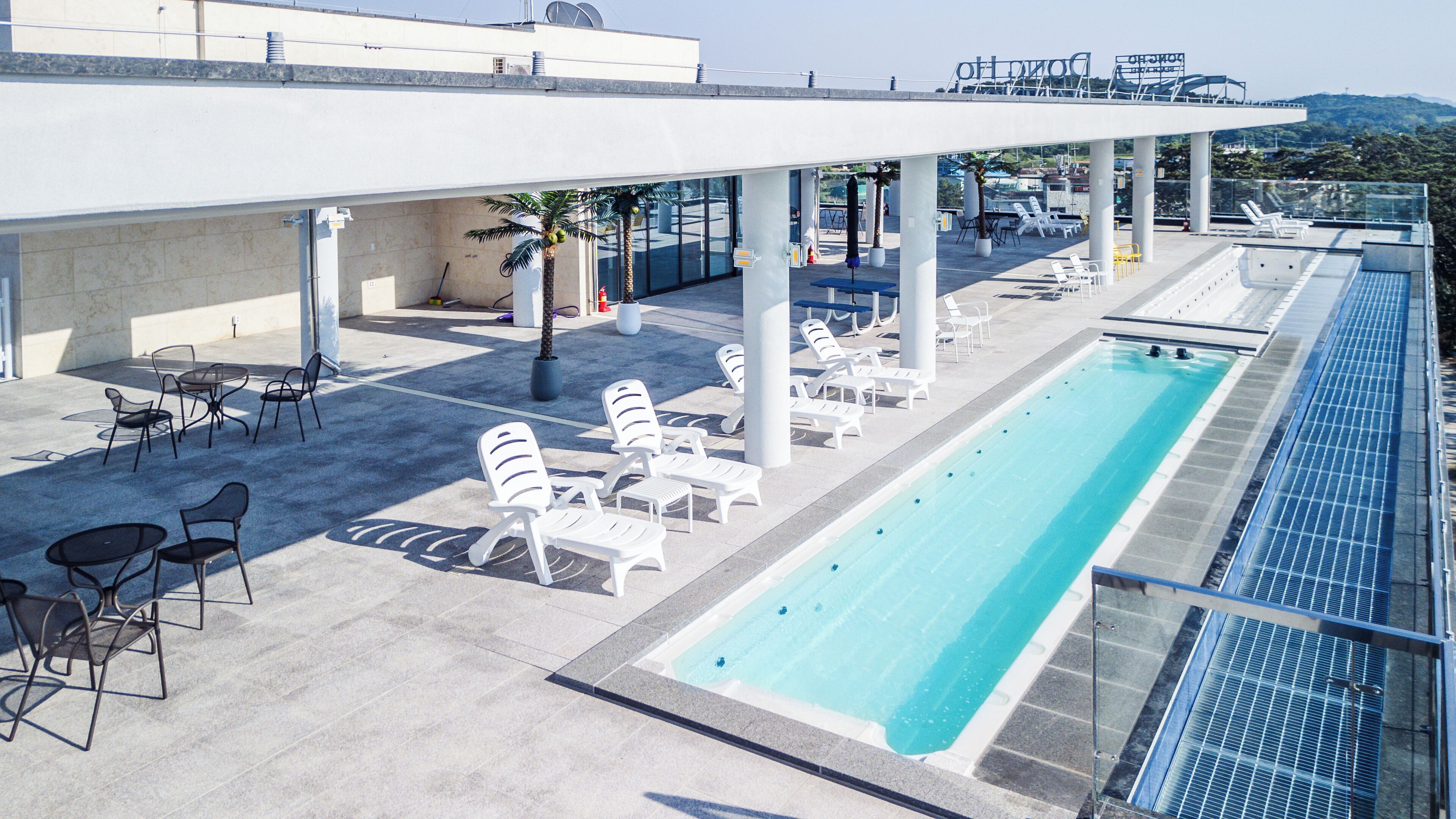 Uma área de piscina no terraço com espreguiçadeiras, piscina e um espaço de estar coberto.