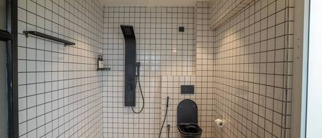Um banheiro pequeno com azulejos, vaso sanitário, chuveiro e secador de mãos.