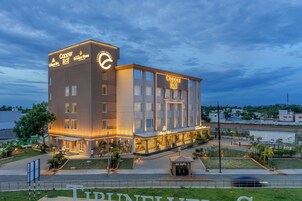 Um hotel moderno com uma placa destacada 'Copper Leaf', apresentando um design contemporâneo e clean, com grandes janelas e fachada bem iluminada.