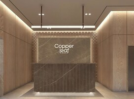 Um balcão de recepção com bancada de mármore e uma placa com a inscrição 'Copper Leaf Hotels'.