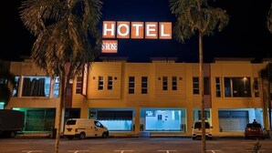 Um hotel com uma placa grande, várias portas de garagem e palmeiras na frente.