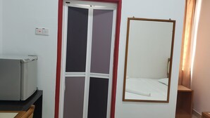 Quarto com cama, espelho, armário e uma pequena mesa.