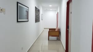 Um corredor com paredes brancas, um banco de madeira e quadros emoldurados.