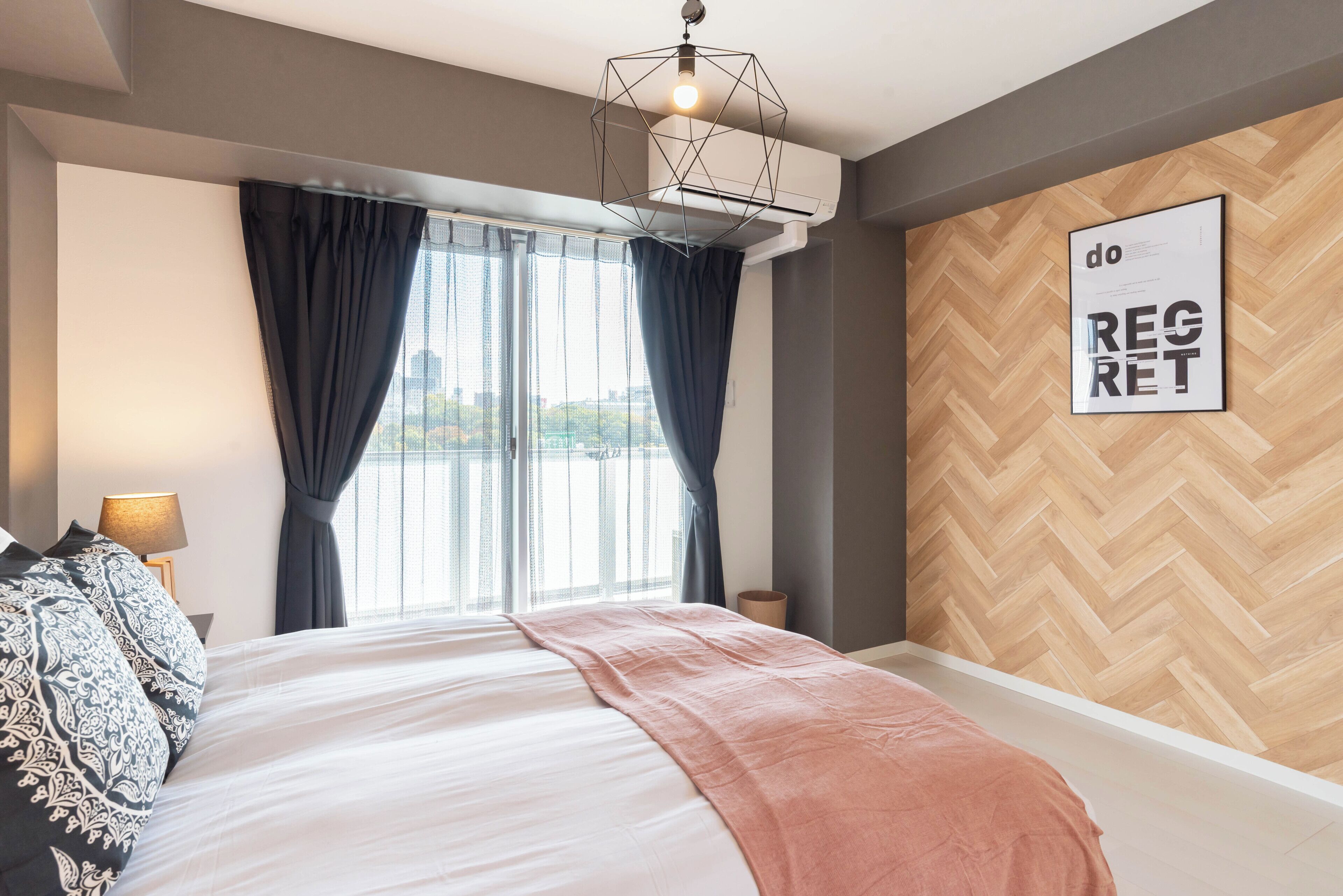 Quarto de hotel moderno com uma cama grande, vista da cidade pela janela e um cartaz fixado na parede.