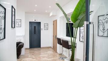 Um corredor com piso de mármore, uma porta e quadros nas paredes.