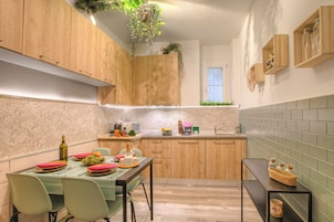 Uma cozinha moderna com armários de madeira, uma mesa de jantar com jogos americanos cor-de-rosa e uma planta pendente.