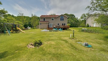 Uma casa de dois andares com varanda, área de recreação e gramado bem cuidado.