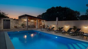 Piscina com espreguiçadeiras e área de estar com lareira de tijolos.