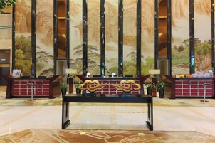 Uma receção com design moderno, ladeada por colunas verticais e um mural com paisagem natural.