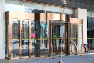 Entrada com porta giratória, painéis de vidro e estrutura metálica.