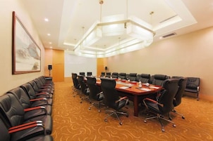 Uma sala de conferência com uma mesa comprida, várias cadeiras e piso coberto por carpete.