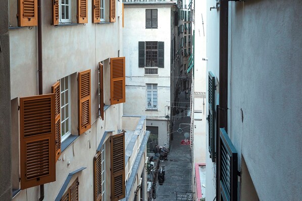 Um beco estreito entre edifícios com persianas de madeira nas janelas.
