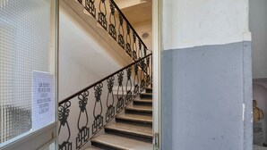 Uma escadaria com grades ornamentadas em preto e parede revestida em azulejos.
