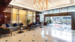 Um lobby moderno com área de estar, um candelabro e janelas amplas.