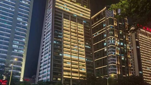 Vista noturna de edifícios altos com janelas iluminadas e arquitetura moderna.