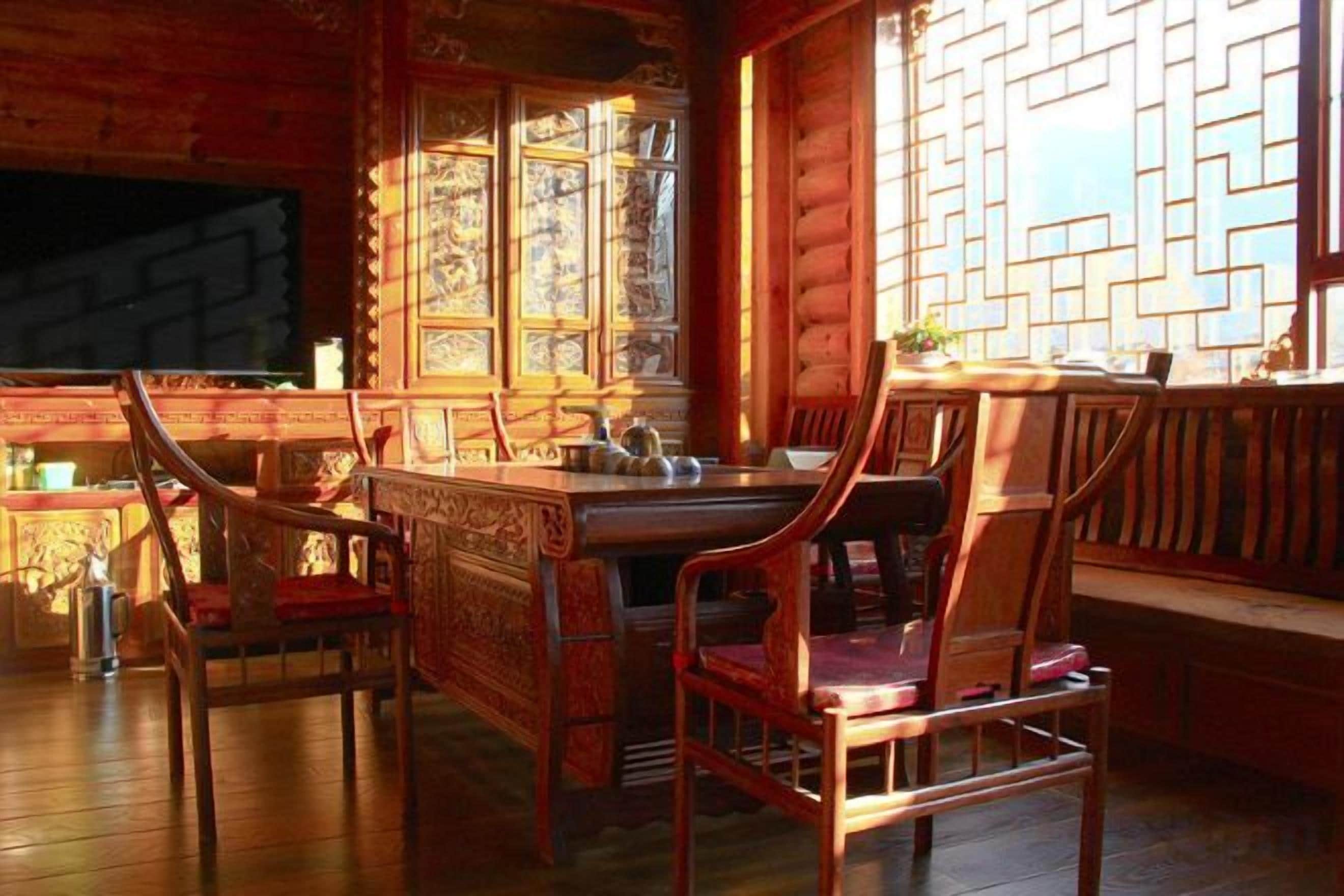 Interior em madeira com uma mesa de jantar e cadeiras, uma janela com persianas estampadas e um banco.