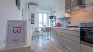 Uma cozinha moderna com forno embutido, um espaço de refeições com mesa e cadeiras, e uma janela grande que proporciona iluminação natural.