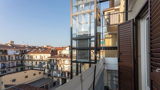 Um edifício alto com várias varandas, janelas amplas e vista para edifícios ao redor.