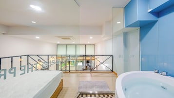 Quarto de hotel moderno com uma banheira grande, varanda envidraçada e escada para área externa.