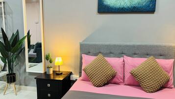 Quarto com cama, mesa de cabeceira, abajur e um espelho grande.