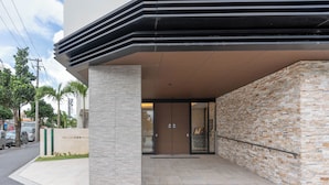 Entrada de um edifício moderno com fachada de pedra, telhado plano e porta visível.