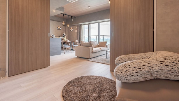 Uma sala de estar moderna com sofá, um tapete redondo e uma grande janela com vista para a cidade.