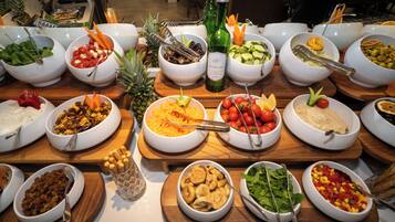 Uma mesa de buffet com diversos alimentos e utensílios.