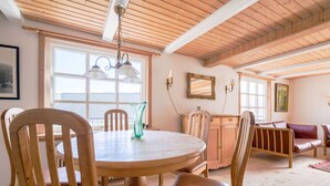 Uma sala de jantar com uma mesa e cadeiras de madeira, um vaso e um armário de madeira.
