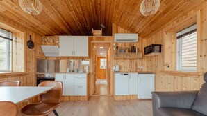 Interior de uma cabana de madeira com cozinha, sala de jantar e sala de estar.