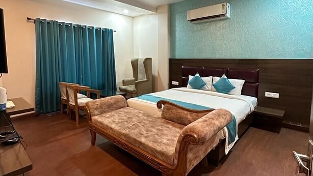Quarto de hotel com cama, sofá, escrivaninha e cadeira.