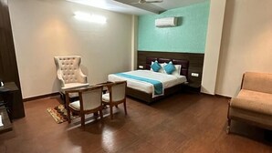 Quarto de hotel com uma cama, uma escrivaninha, uma cadeira e um sofá.