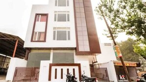 Um edifício moderno com fachada branca e detalhes em castanho, apresentando um painel vertical grande e castanho no lado direito.
