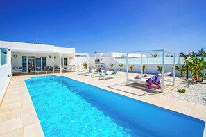 Uma área de piscina moderna com espreguiçadeiras e uma estrutura envidraçada.