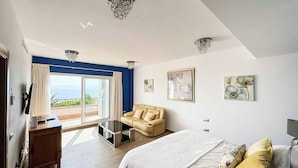 Quarto de hotel com cama, sofá, mesa pequena e vista para o exterior.
