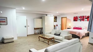 Uma sala de estar moderna com sofá, mesa de centro e cama com colcha rosa.
