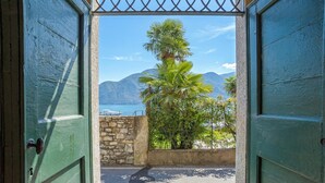 Uma porta que dá para uma varanda com vista para o mar e montanhas.