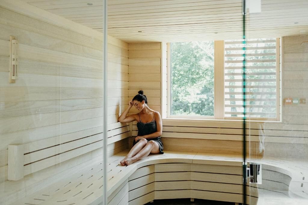 Uma sauna com um banco curvo e uma janela que oferece vista para as árvores.