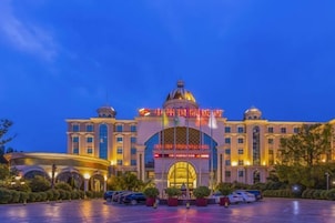 Um hotel imponente com uma cúpula central, várias alas e uma entrada bem iluminada.