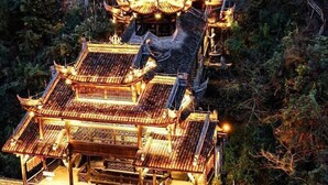 Um templo tradicional com vários níveis, arquitetura elaborada e uma escadaria que leva até ele.