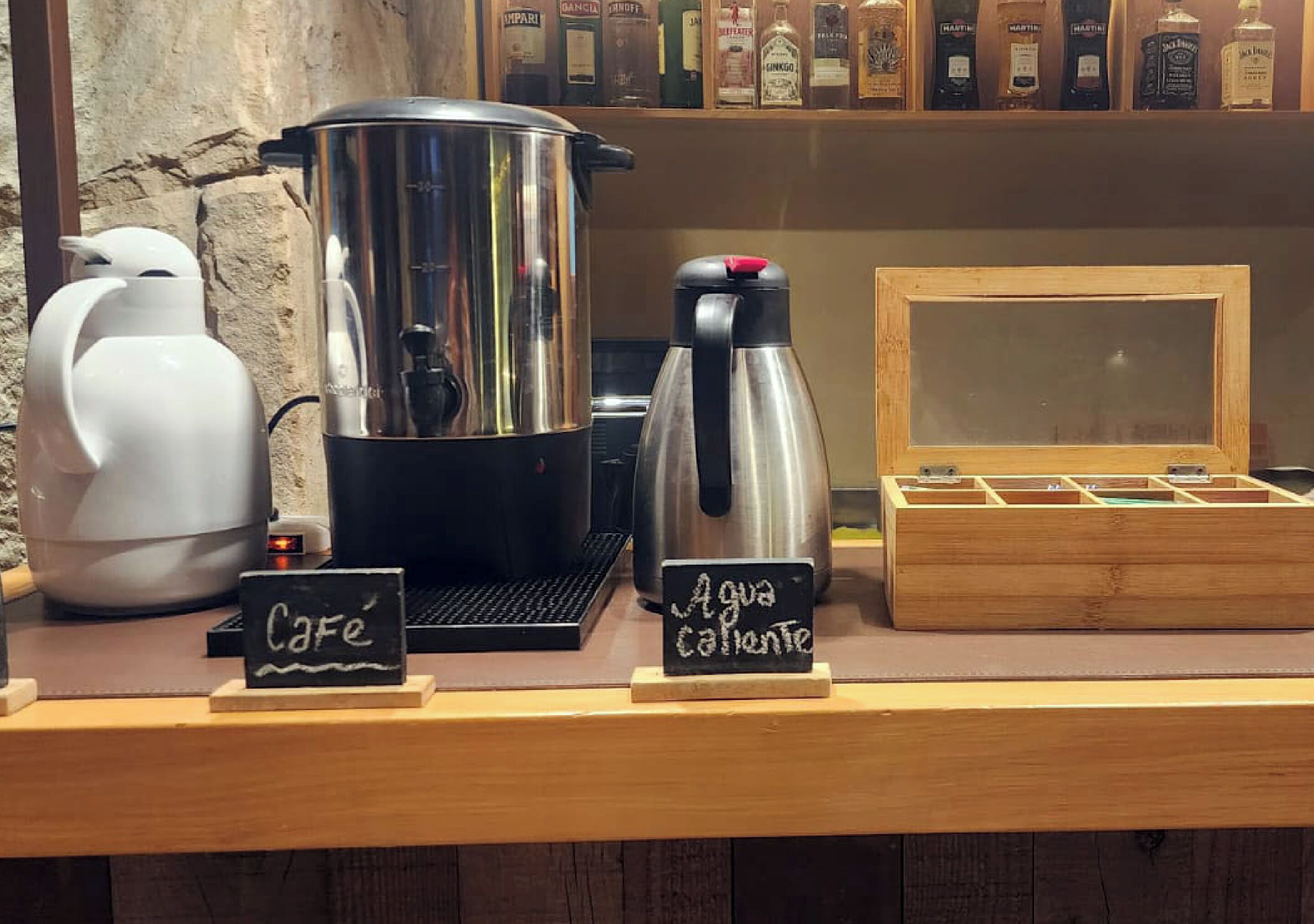 Estação de café com cafeteira, dispensador de água e um aviso indicando 'Café' e 'Água quente'.